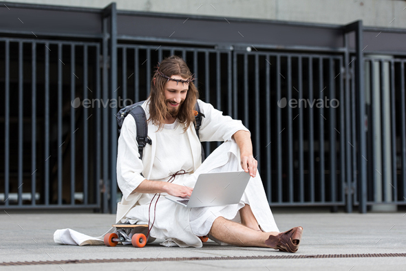 smiling Jesus in robe and crown of thorns sitting on skateboard and ...