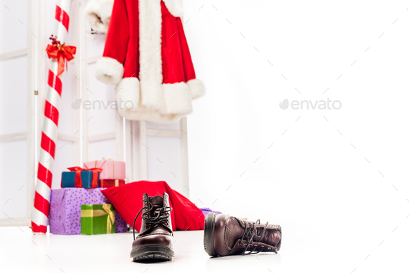 close up view of boots and pile of gift boxes and santa costume on ...