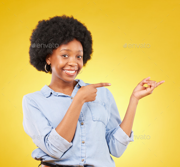 Happy, portrait of a black woman in studio pointing at mockup space for advertising or marketing ...