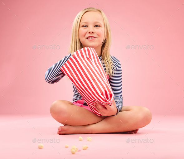 Popcorn, snack and happy girl in a studio with pink background sitting ...