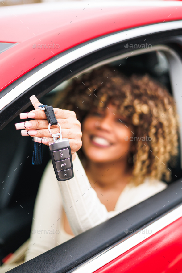 Afro woman in red car showing her new keys, renting a car concept Stock ...