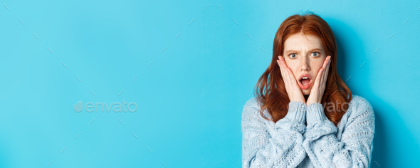 Close-up of shocked redhead girl staring at something displeasing ...