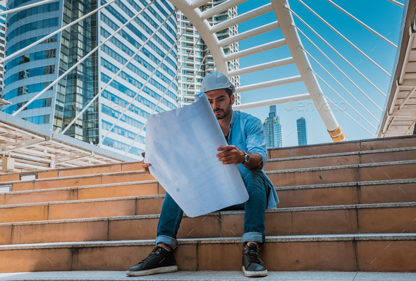 Engineer look at project blueprints for thinking about building project ...