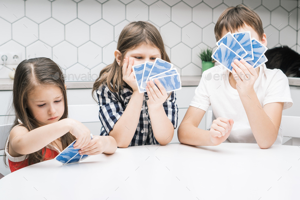 Funny photo three children looking at blue playing cards in hands with ...