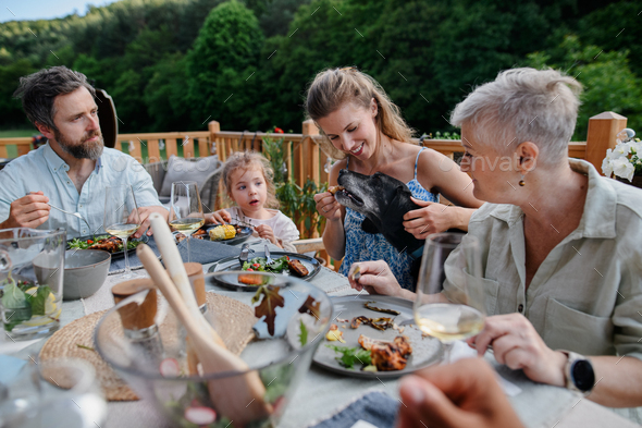 Multigenerational family eating dinner at barbecue party. Stock Photo ...