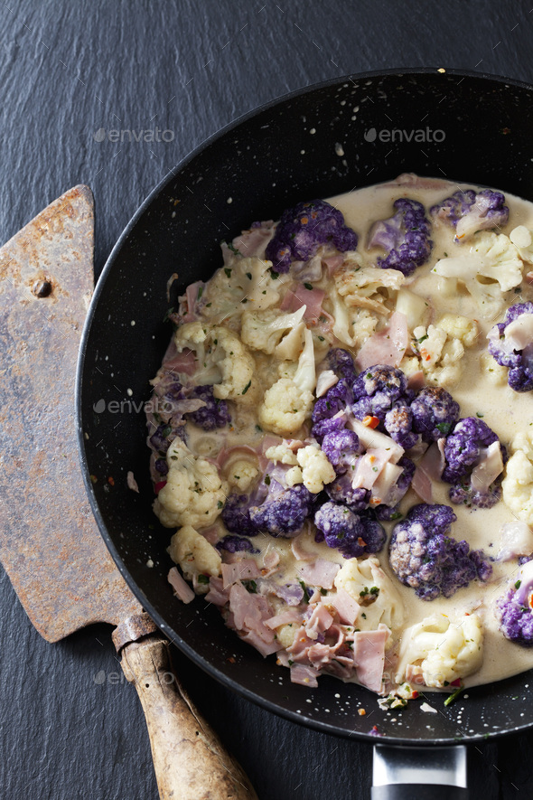 Pan of cauliflower florets with cooked ham and spices in cream sauce ...
