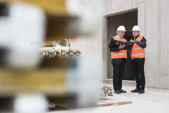 Two men wearing safety vests talking on construction site Stock Photo ...
