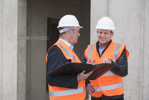 Two men wearing safety vests talking on construction site Stock Photo ...