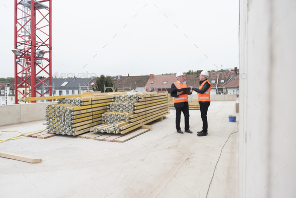 Two men wearing safety vests talking on construction site Stock Photo ...