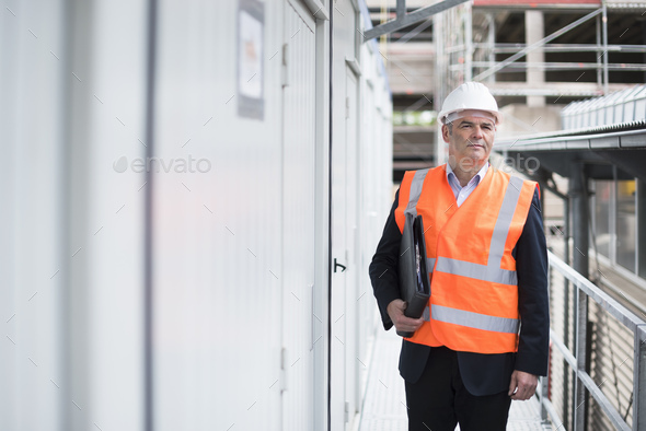 Man with documents wearing safety vest on construction site Stock Photo ...