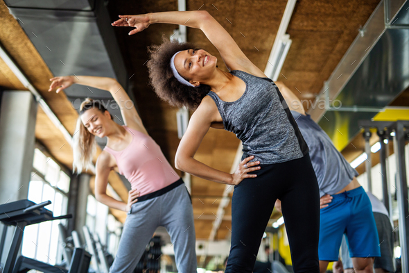 Group of young fit people, friends doing exercises in gym to stay ...