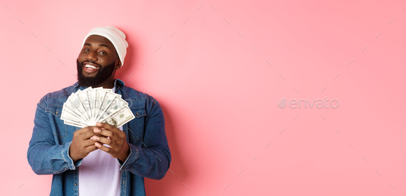 Satisfied rich african-american man showing money, smiling pleased and ...