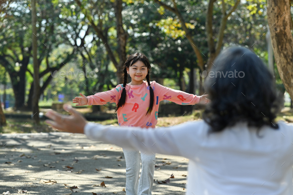Cheerful little asian girl running into running to hug grandmother ...