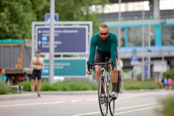 A cyclist man rides a bike in a city park along a bike path. Stock ...