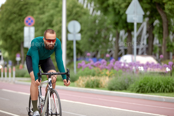 A cyclist man rides a bike in a city park along a bike path. Stock ...