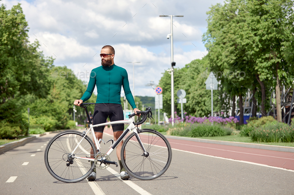 A cyclist man rides a bike in a city park along a bike path. Stock ...
