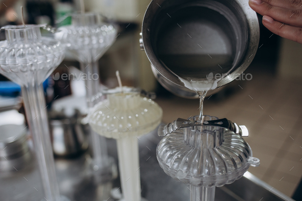 Creative occupation of candle making showing the pouring of liquid wax ...