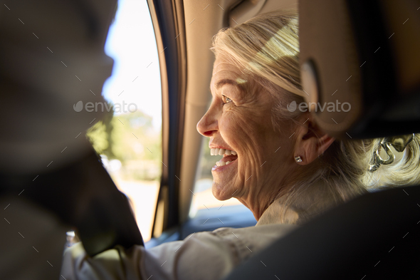 Smiling Senior Female Driver Looking Out Of Car Window Enjoying Day ...