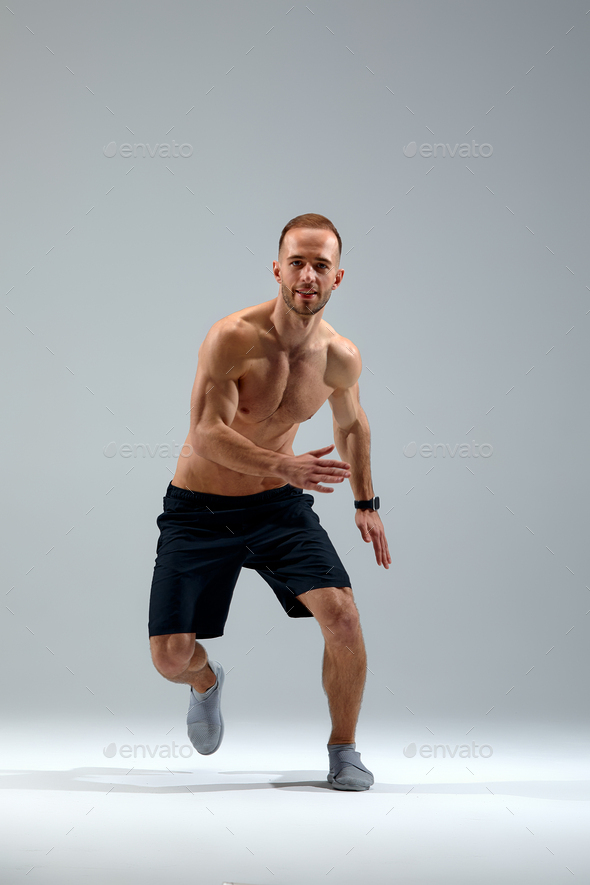 Developing endurance. Male athlete in motion isolated over gray studio ...