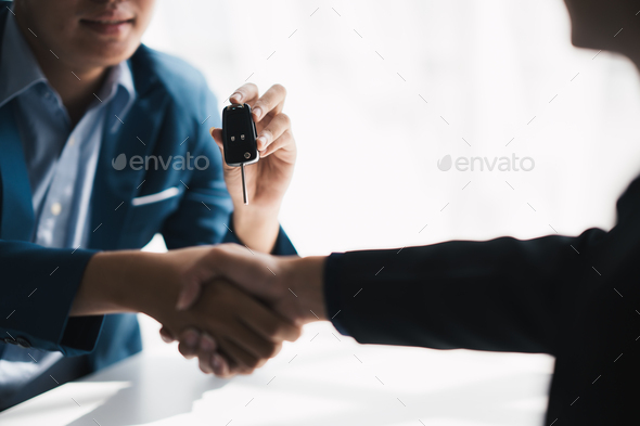 Salesman agent and customer shake hand, giving auto key of vehicle to ...