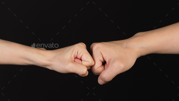 Punch to punch hand sign on black background. Stock Photo by puibunny