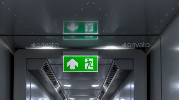 Green emergency exit sign showing the way to escape. Fire exit in the ...