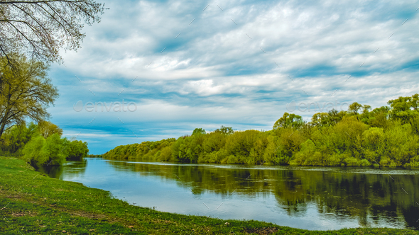 Beautiful spring green landscape with flowing river and fluffy clouds ...