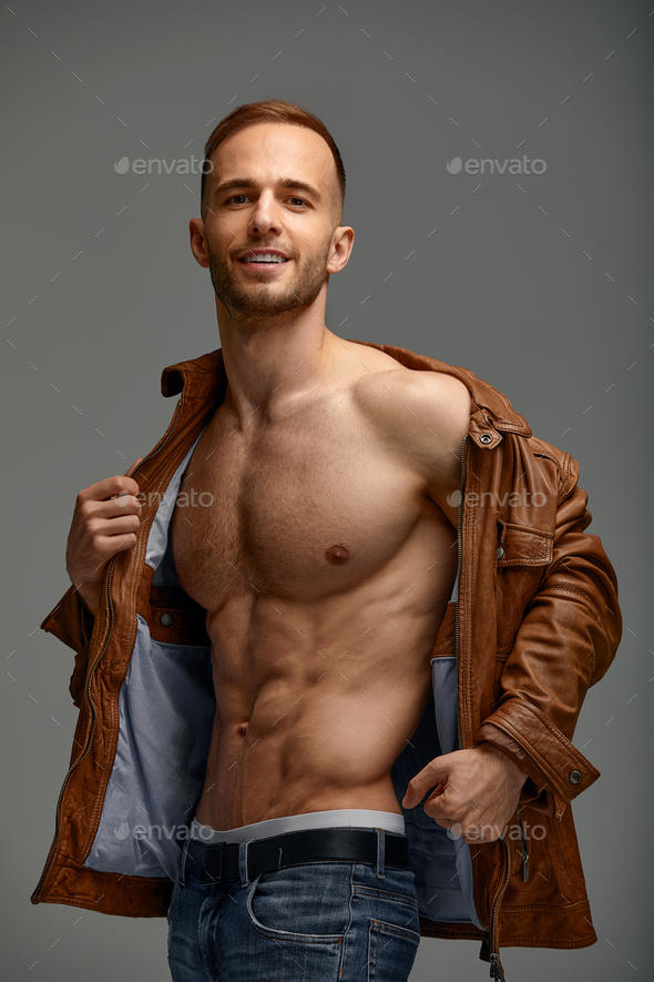 Portrait of a handsome male model posing shirtless in a brown leather ...