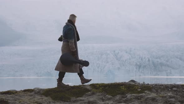 Man With Guitar Case And Greatcoat Walking Along Ridge By Glacier ...