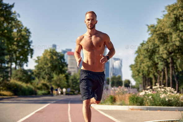 caucasian man jogging on the running track - Blonde male athlete in ...