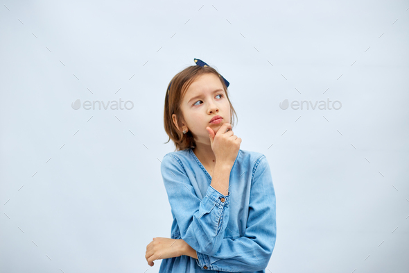 Thoughtful teen girl child wearing jeans dress with finger thinking ...