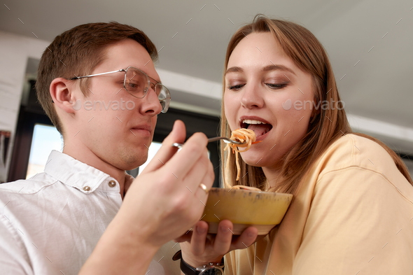 Smiling loving husband feeding wife, young couple enjoying tender ...