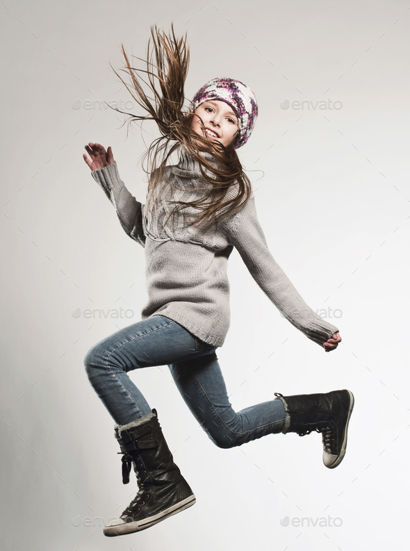 Girl (8-9) wearing woolly hat jumping, smiling, portrait Stock Photo by ...