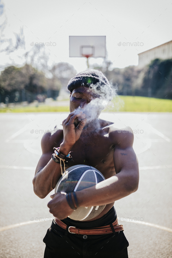 Barechested basketball player on court smoking a joint Stock Photo by ...