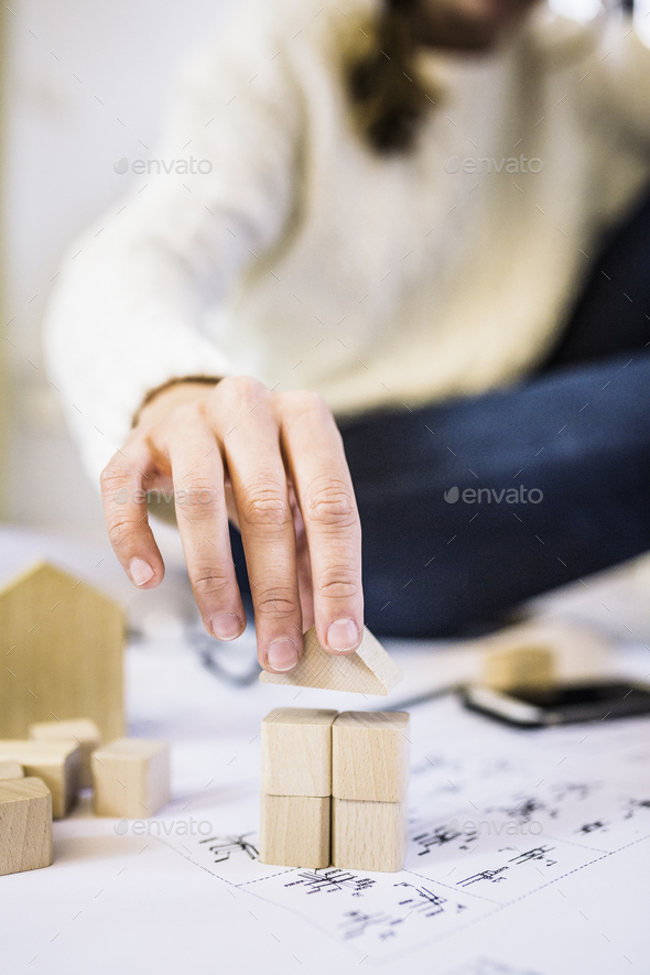 Woman placing building brick house on blueprint Stock Photo by westend61