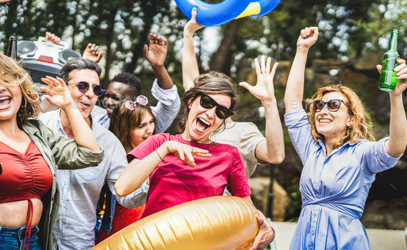 Mixed age diverse people having fun out side cheering with boombox at ...