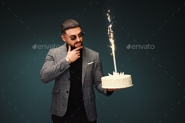Handsome young man holding cake in his hand with lighted sparkling ...