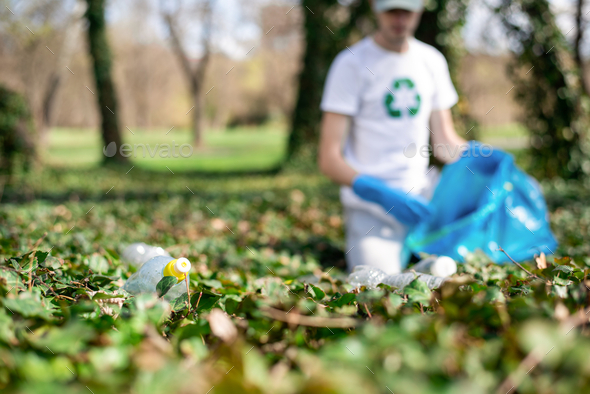 Man collecting plastic garbage in a polluted park Stock Photo by frimufilms