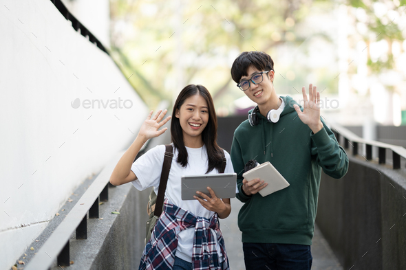Female college student and male college student waving their hands to ...