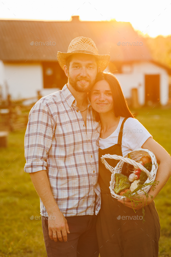 Portrait of young happy farmer couple holding basket with fresh organic ...