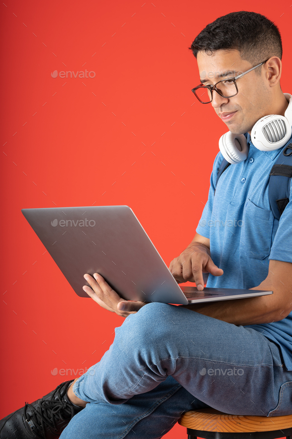 Serious and concentrated young college man, sitting cross-legged using ...