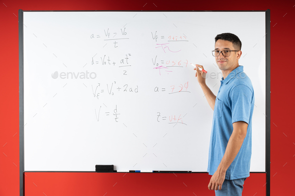 Young male smiling , explaining math exercises on a white board, with a ...