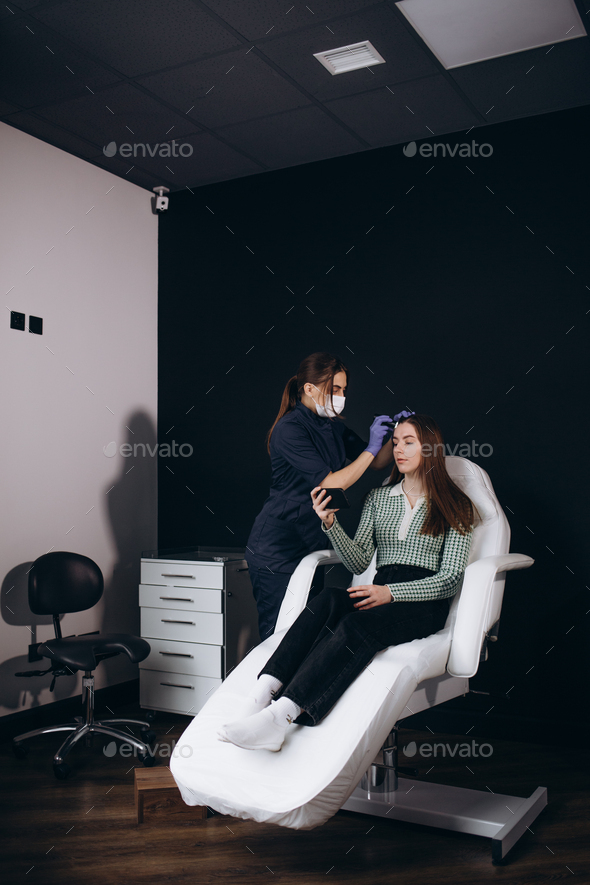 Doctor trichologist examines woman patient's hairs using trichoscope in ...