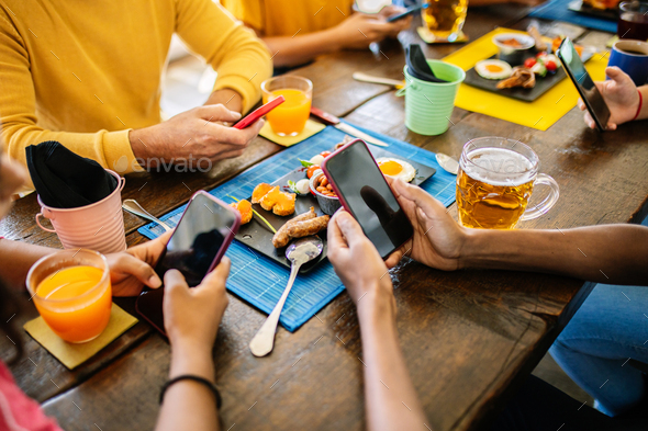 Close up view of young people hands using mobile phone at restaurant ...