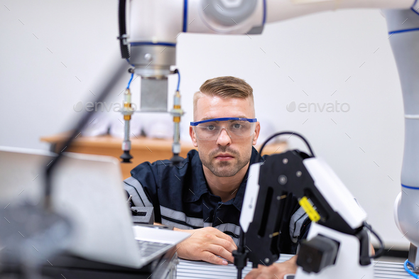 Engineer sitting in robot fabrication room quality checking robot arm ...