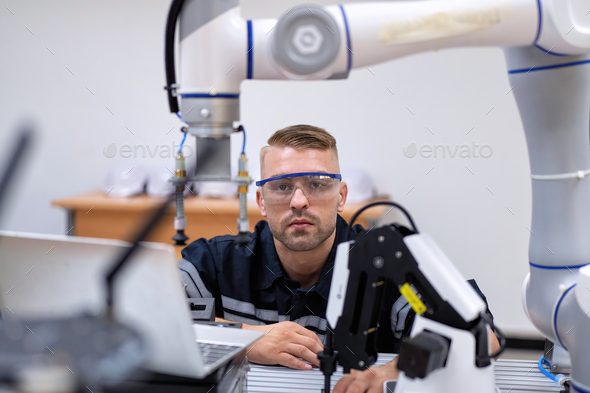 Engineer sitting in robot fabrication room quality checking robot arm ...