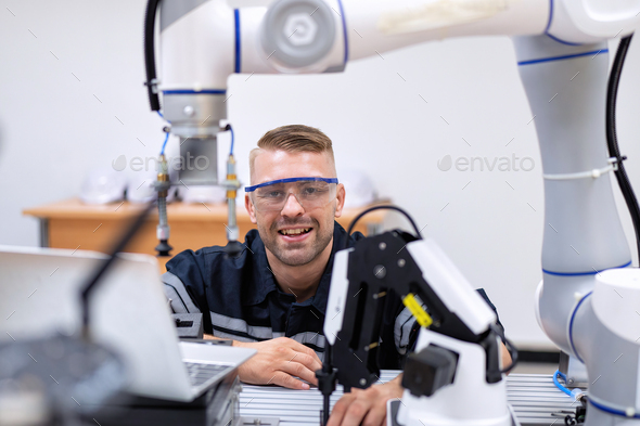 Engineer sitting in robot fabrication room quality checking robot arm ...