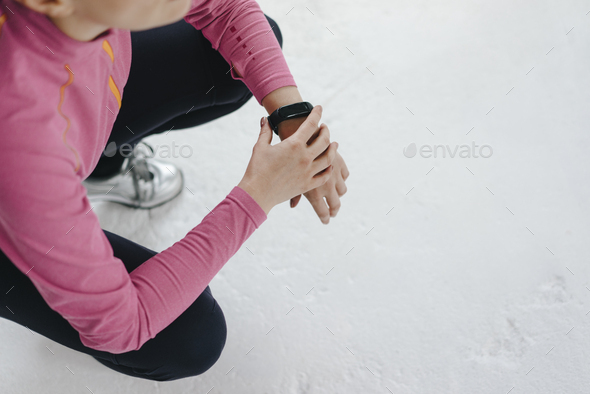 Woman in sportswear crouching wearing activity band Stock Photo by ...