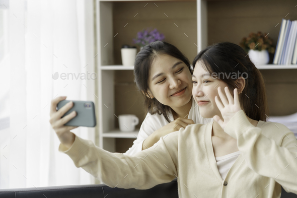 Asian lesbian couple, LGBTQ. Lesbian couple holding smartphone and posing while taking selfie ...