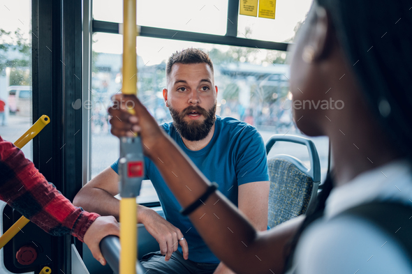 Multiracial friends talking while riding a bus in the city Stock Photo ...